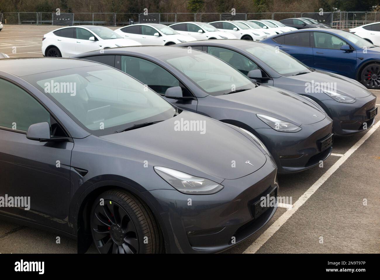 Tesla Electric vehicle EV cars waiting at a delivery collection car hub ...
