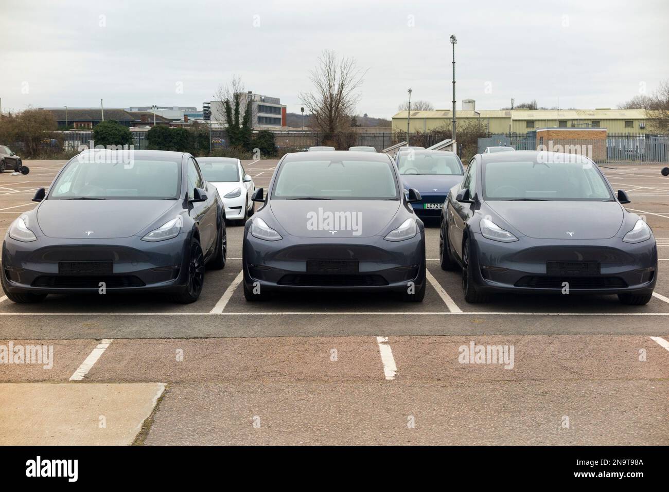 Tesla Electric vehicle EV cars waiting at a delivery collection car hub ...