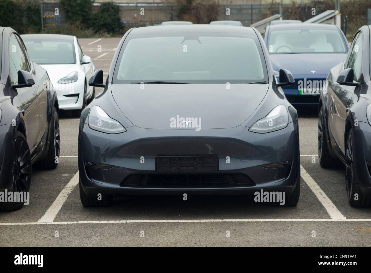 Tesla Electric vehicle EV cars waiting at a delivery collection car hub ...
