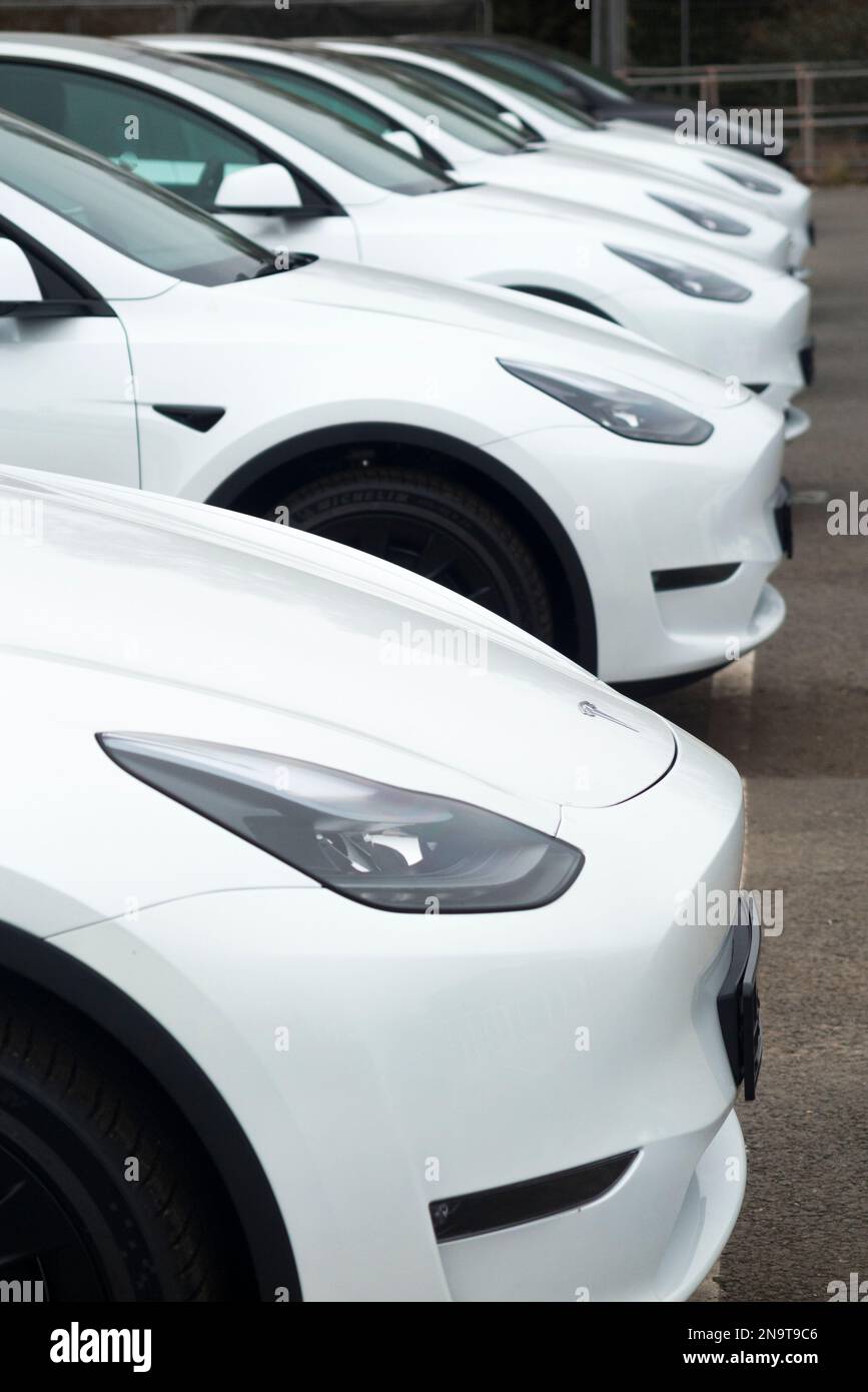 Tesla electric vehicle EV cars waiting at a delivery collection car hub ...