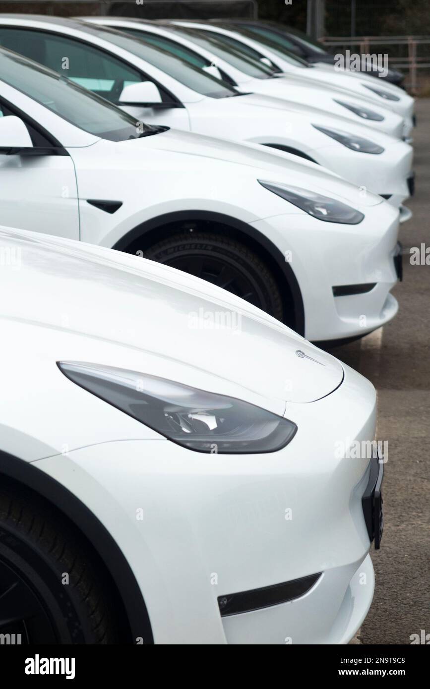Tesla electric vehicle EV cars waiting at a delivery collection car hub ...