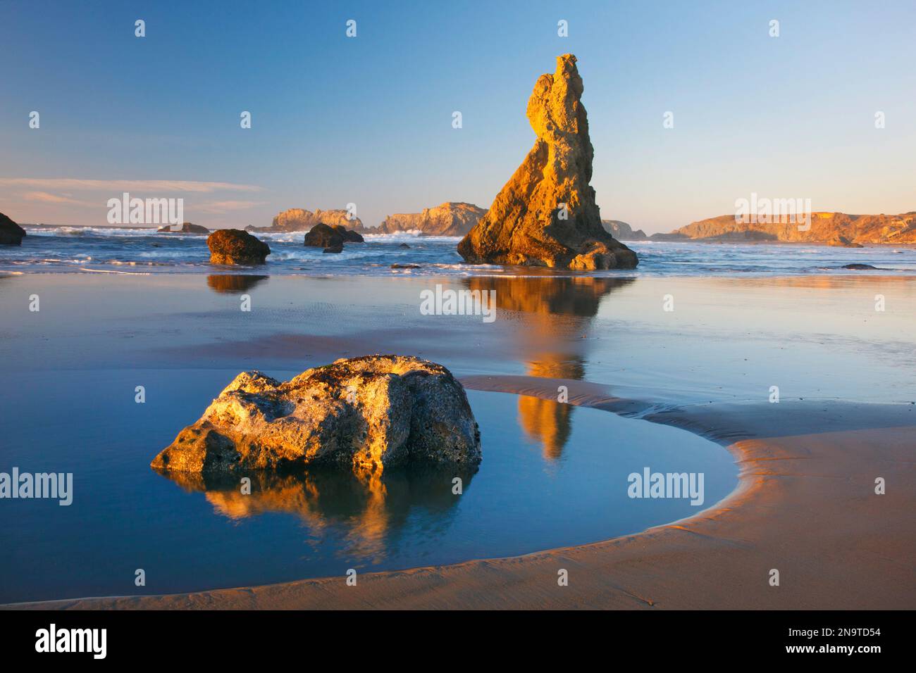Rock formations reflected on the wet sand and tide pools on Bandon ...