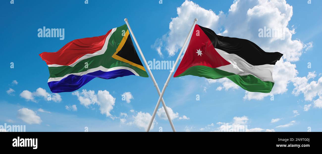 two crossed flags Jordan and South Africa waving in wind at cloudy sky ...