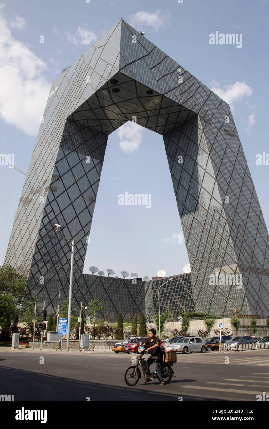 A Chinese man bicycles in front of the headquarters of China Central ...