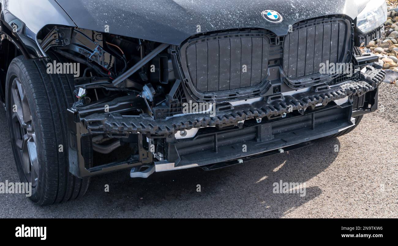 A black BMW at a dealership with front end damage from an accident ...