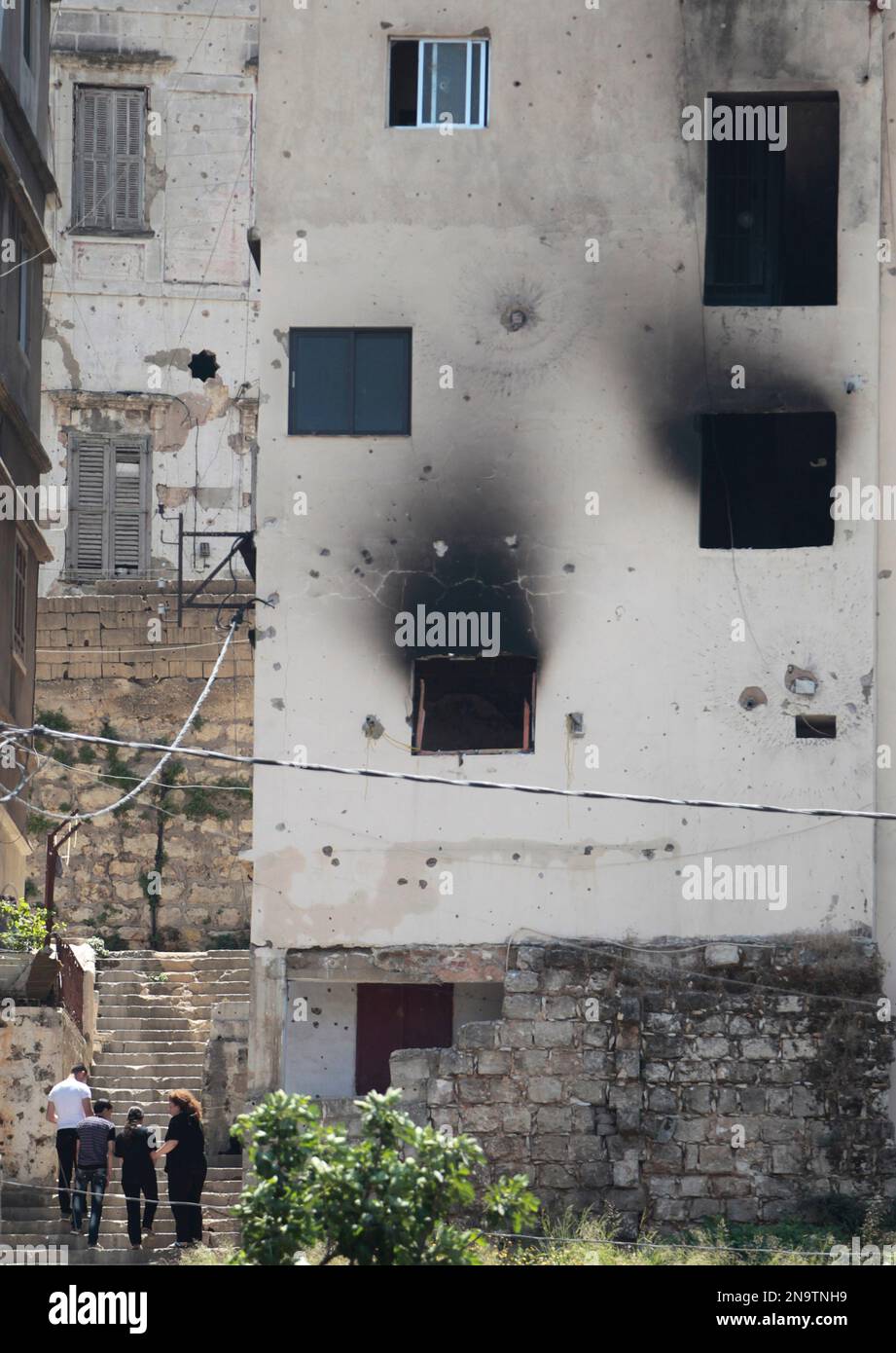 Lebanese Alawite citizens, left, walk next to building that was damaged ...