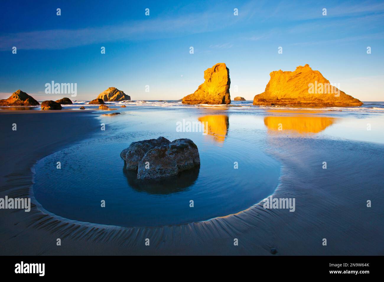 Rock formations at low tide on Bandon Beach with the moon setting in ...