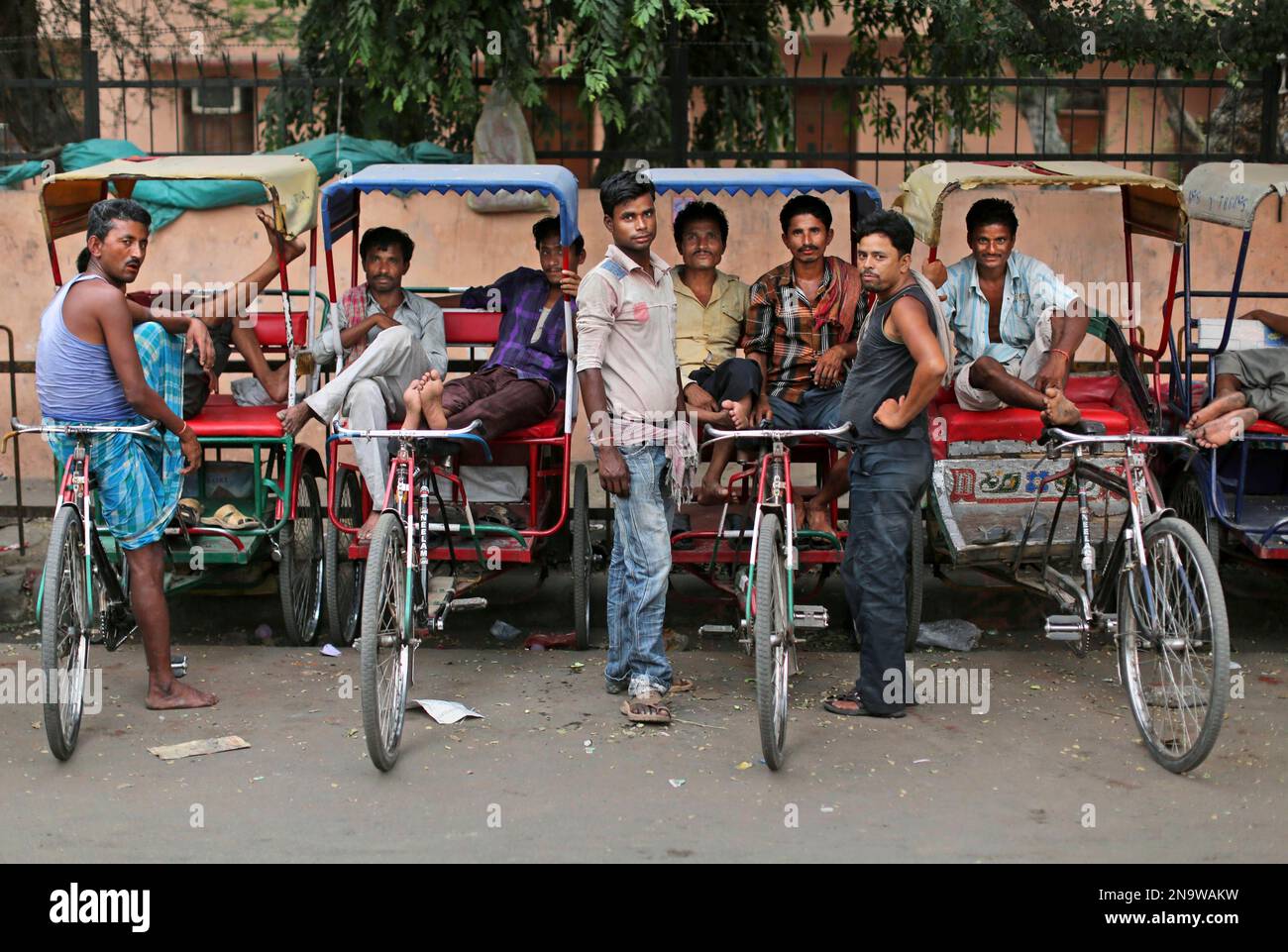Indian bicycle rickshaw pullers stand together as they wait for ...