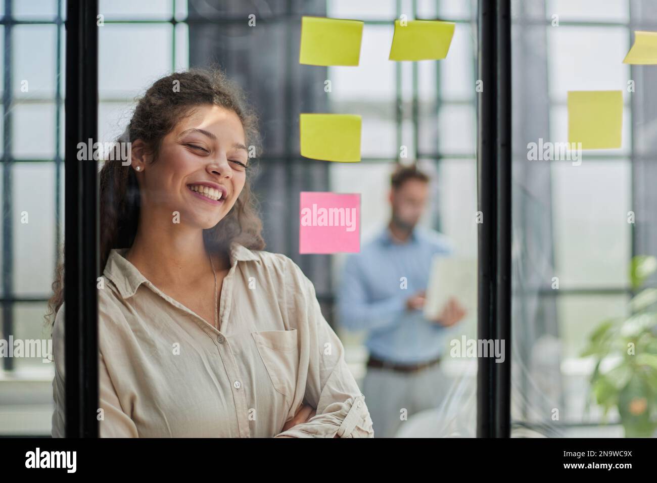 Smiling business woman looking out the window Stock Photo - Alamy