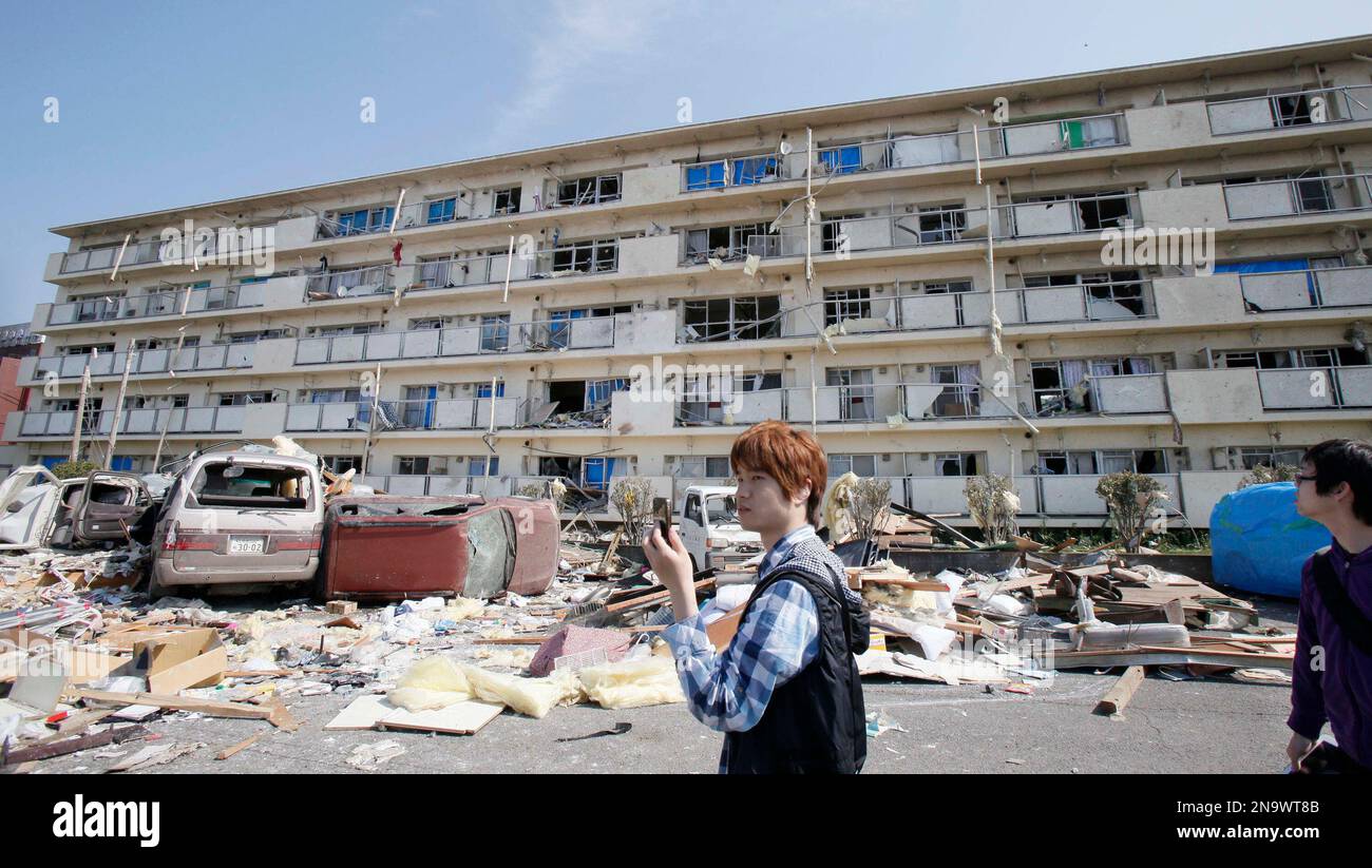 People look at a damaged apartment after a tornado in Tsukuba city ...
