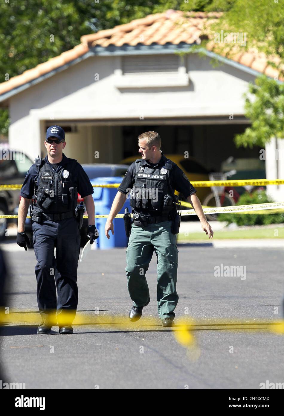 Gilbert police officers walk inside the police tape outside a crime ...