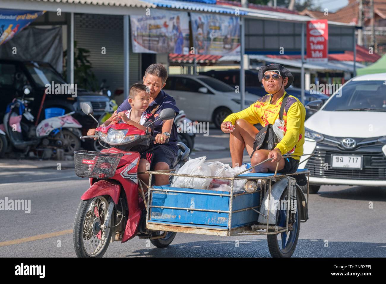 A motorcycle rider driving with a boy on his bike, while a man sit ...