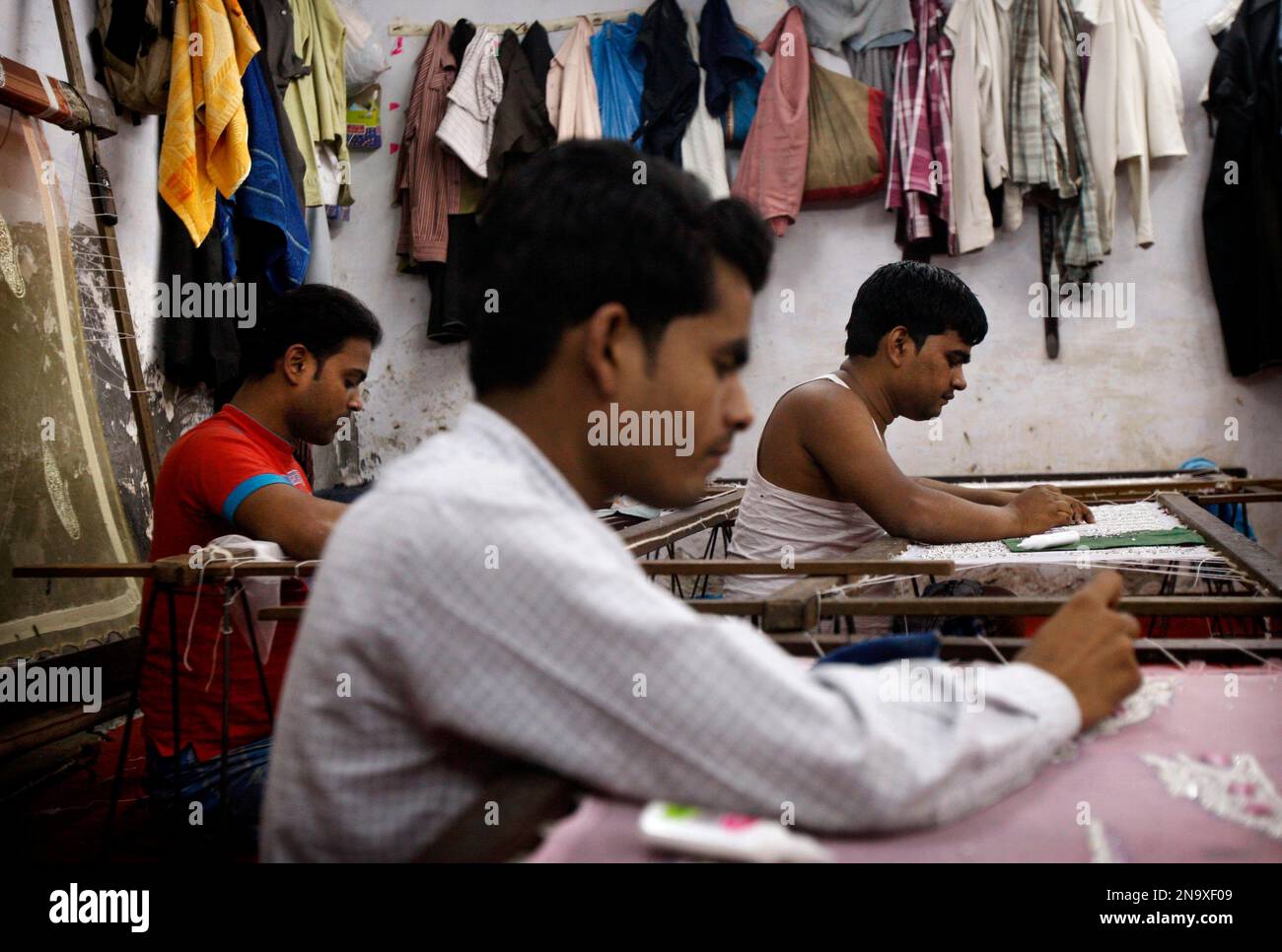 Indian laborers work on embroidery of beads on saris, a traditional ...