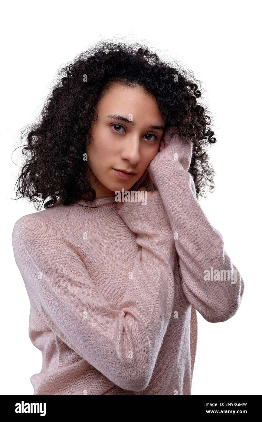 Portrait of young curly-haired woman in pink wool sweater. she is very ...