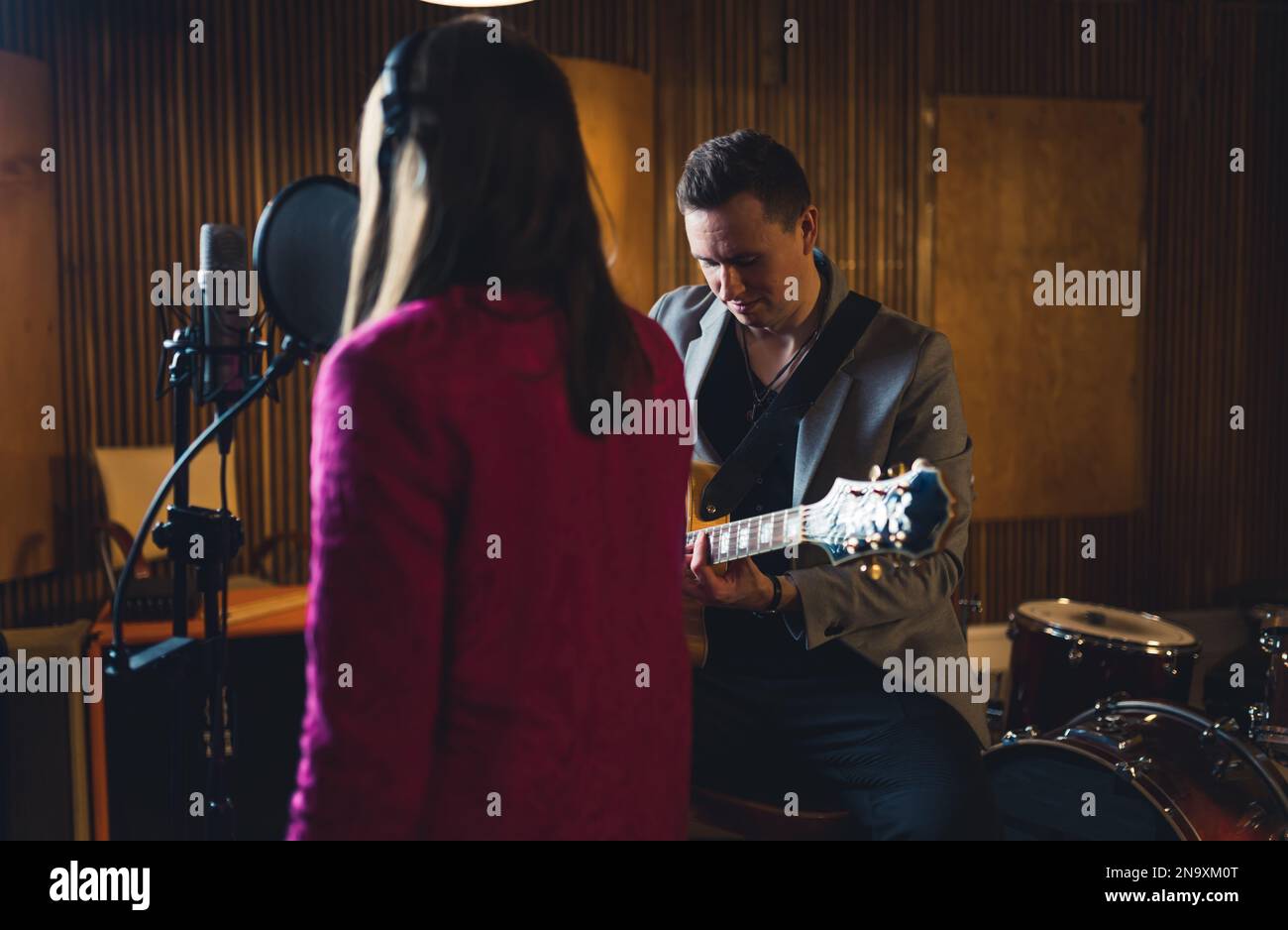 Recording in a studio guitarist and singer back shot. High quality ...