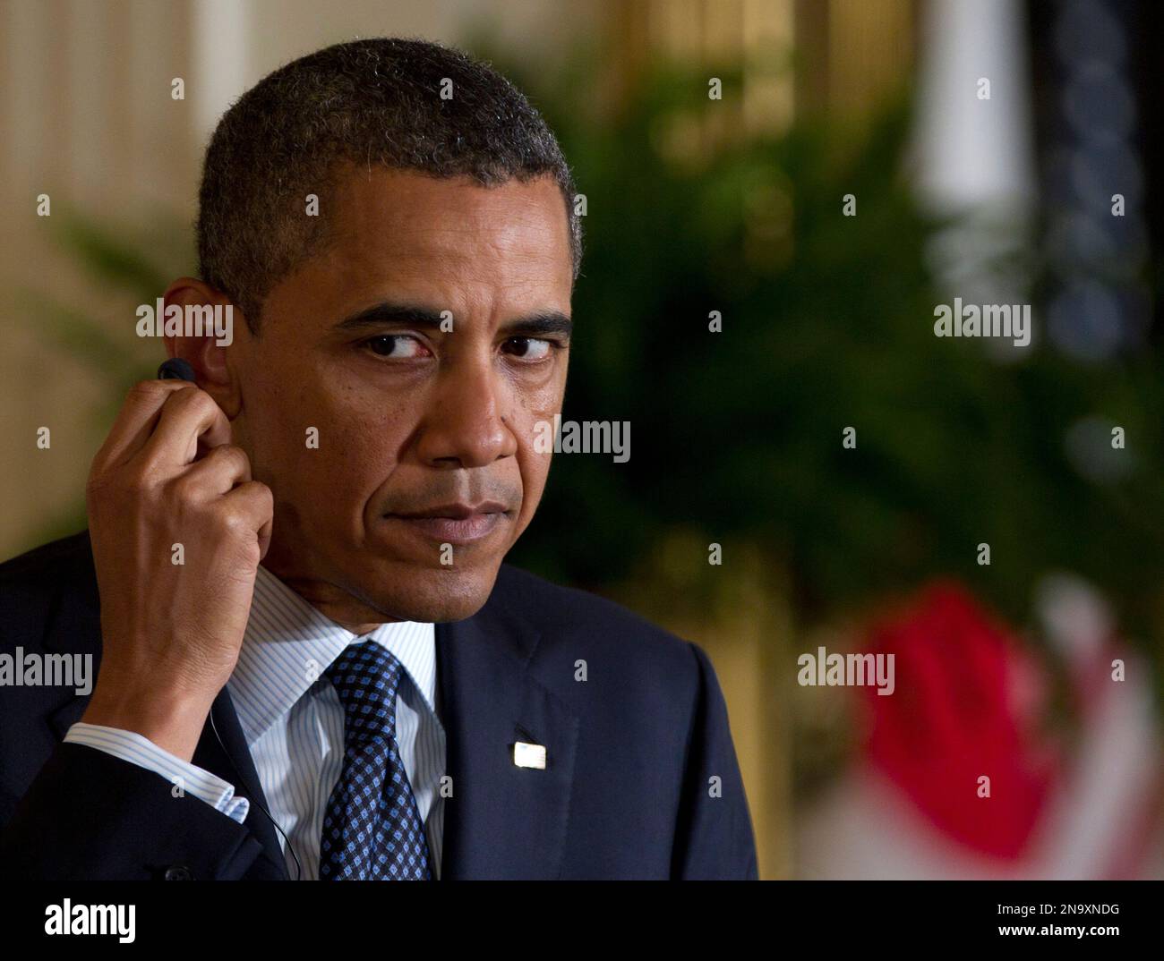 President Barack Obama adjusts his ear piece during his joint news ...