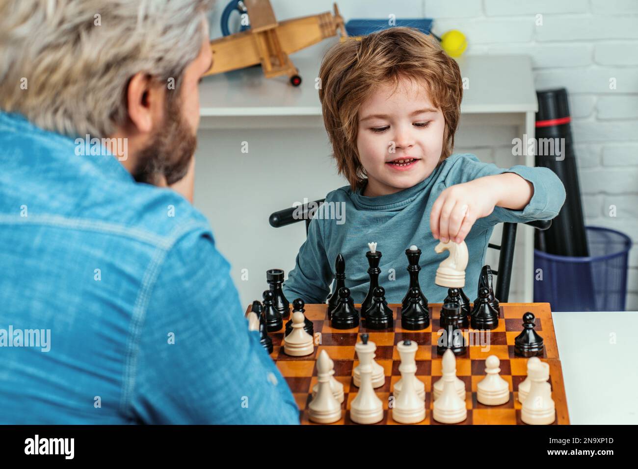 Father teaching son. Son are playing chess wit father and smiling at ...
