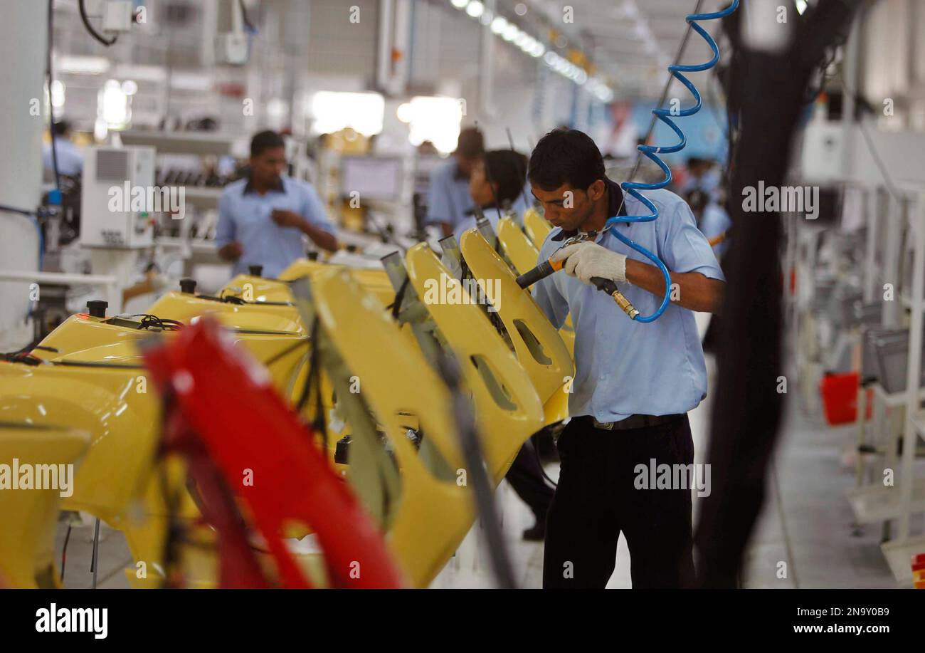 An Indian worker works on Vespa scooters at its manufacturing unit in ...