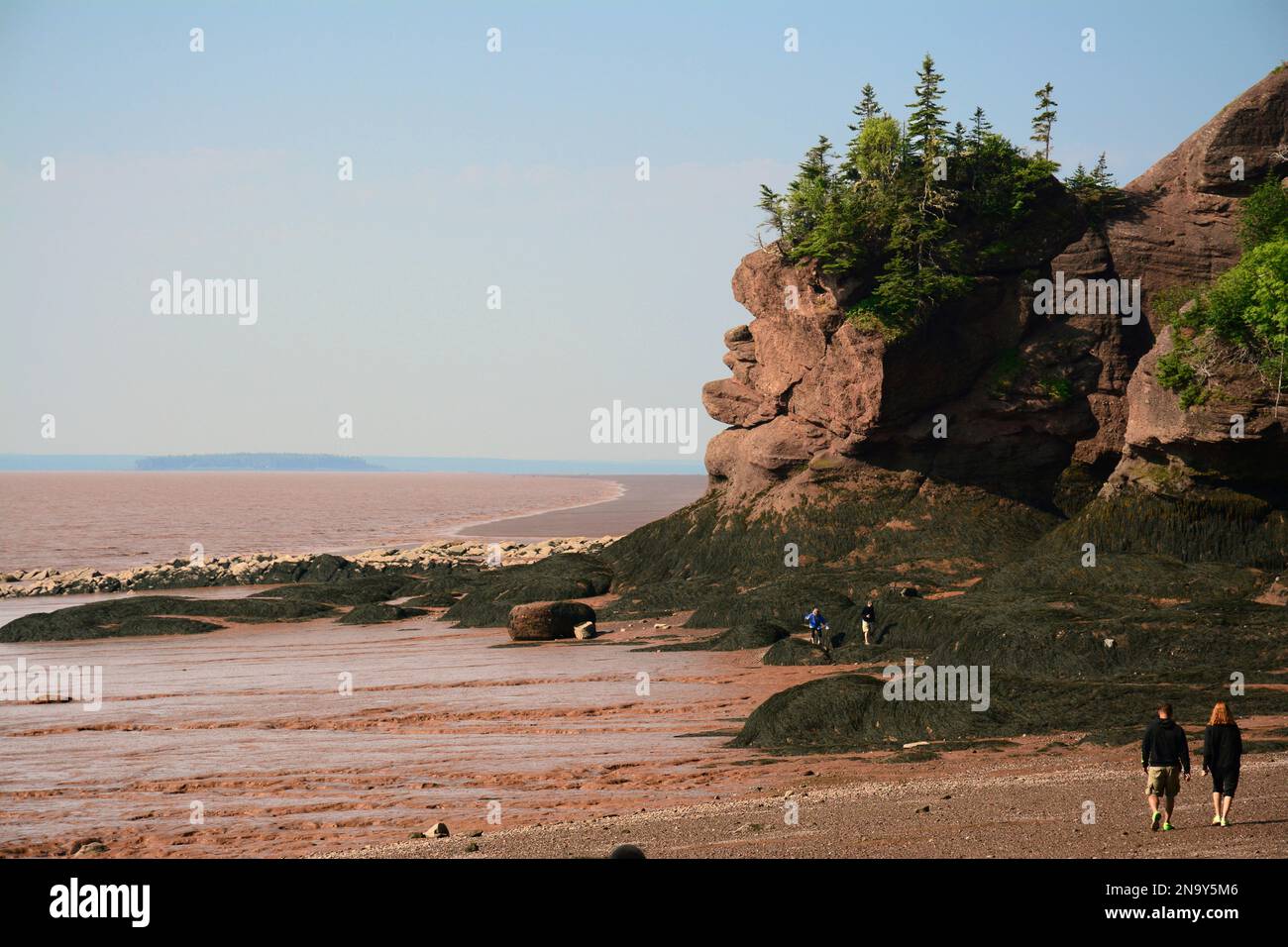 Rock formations, tourists and the Bay of Fundy at Hopewell Rocks, NB ...