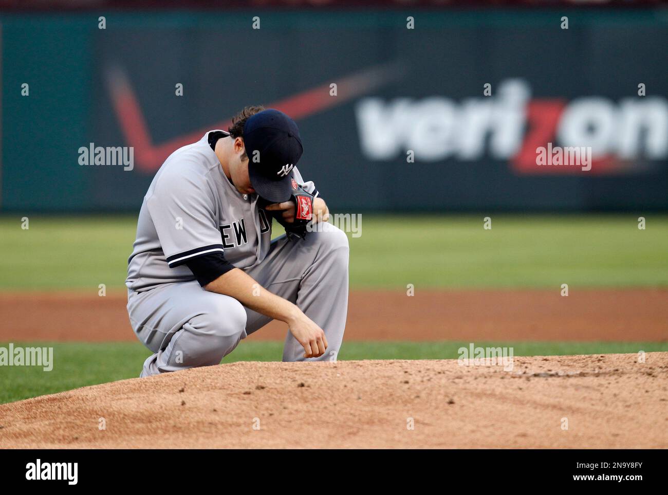 New York Yankees starting pitcher Phil Hughes kneels behind the mound ...