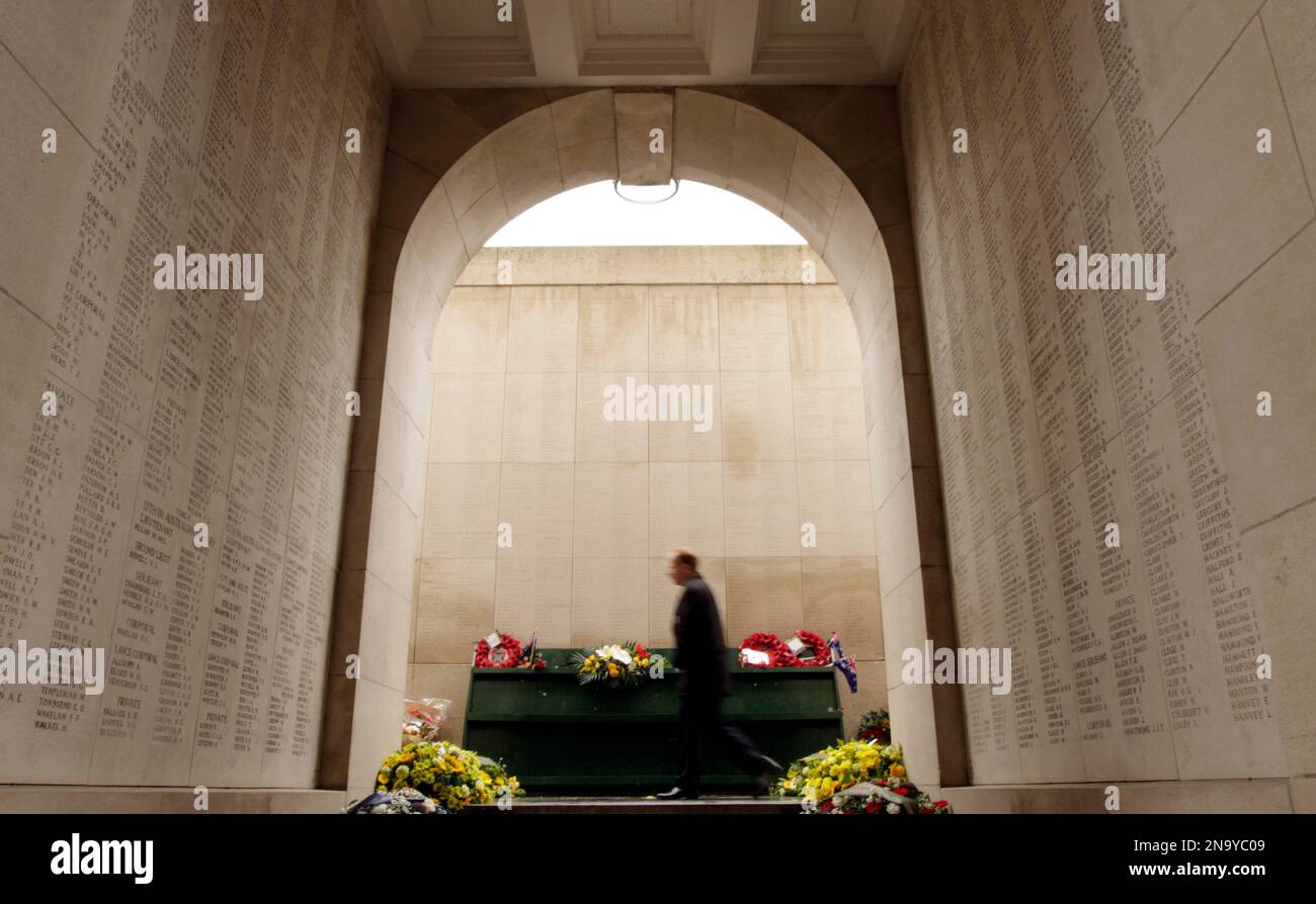 A man walks by wreaths and names on a memorial wall during an Anzac day ...