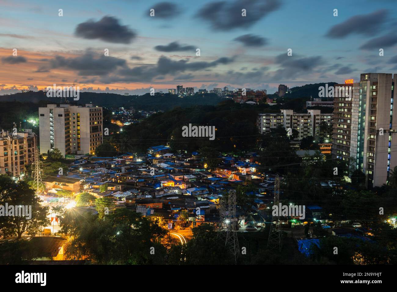 View of slum at sunset surrounded by high-rise buildings; Mumbai ...