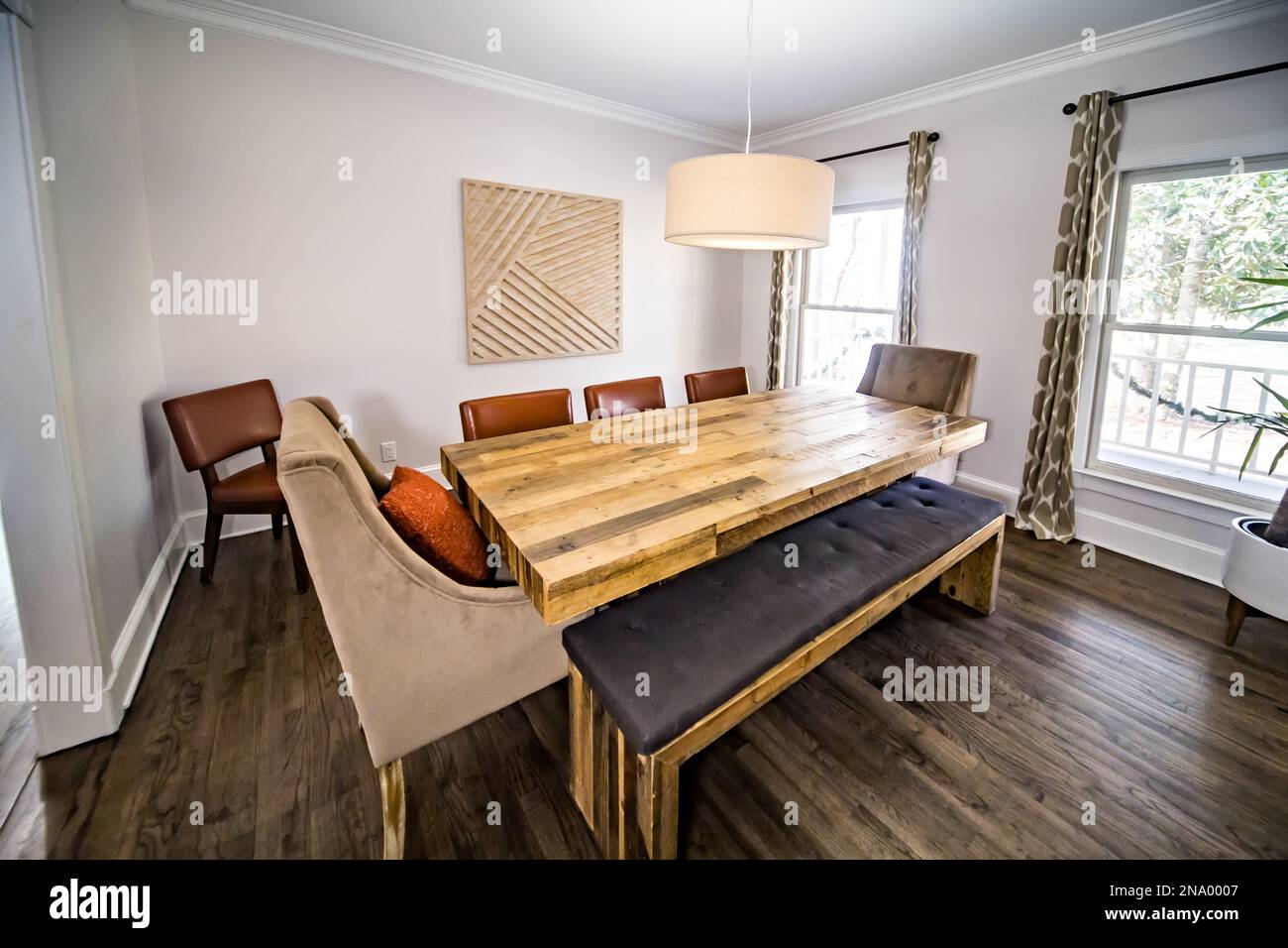 A modern dining room with a stained with a stained wood table, bench ...