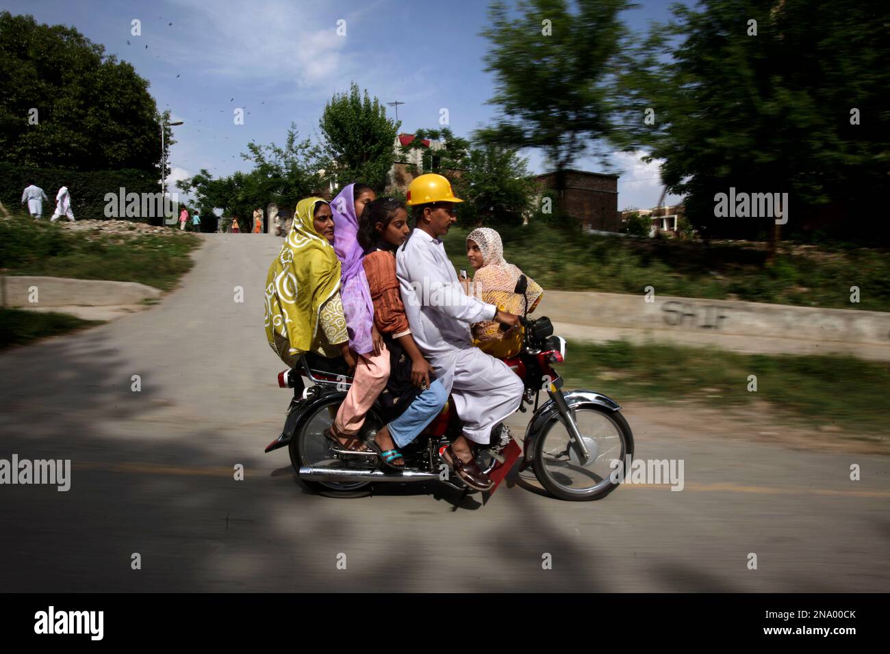 A Pakistani couple and their three daughters, ride a motor bike along a ...