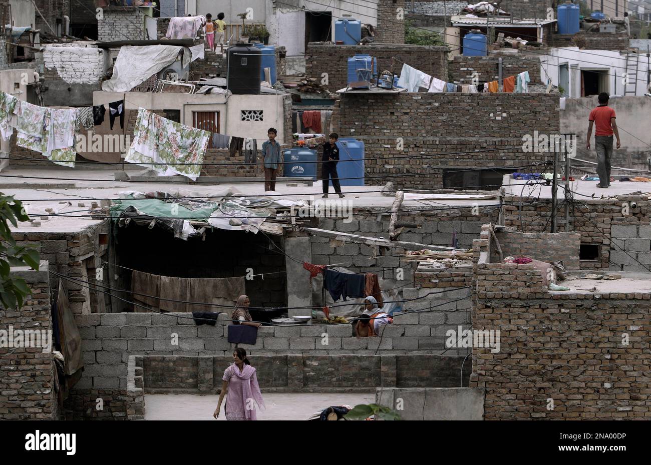 Two Pakistani boys, center, fly a kite on the rooftop of a house in a ...