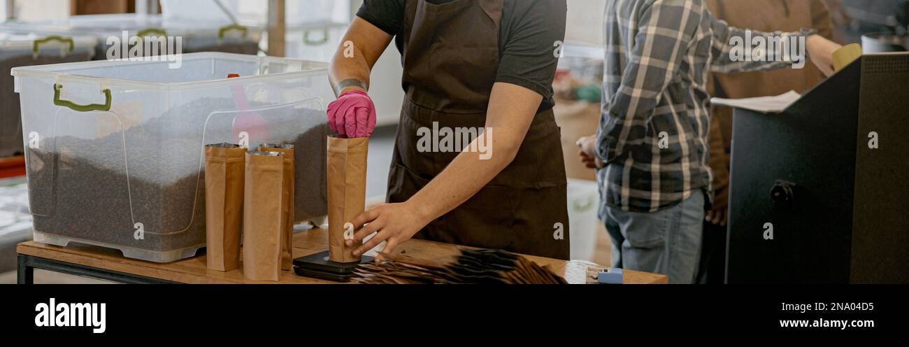 Business owner weighs paper bag with coffee beans on a scale at coffee ...