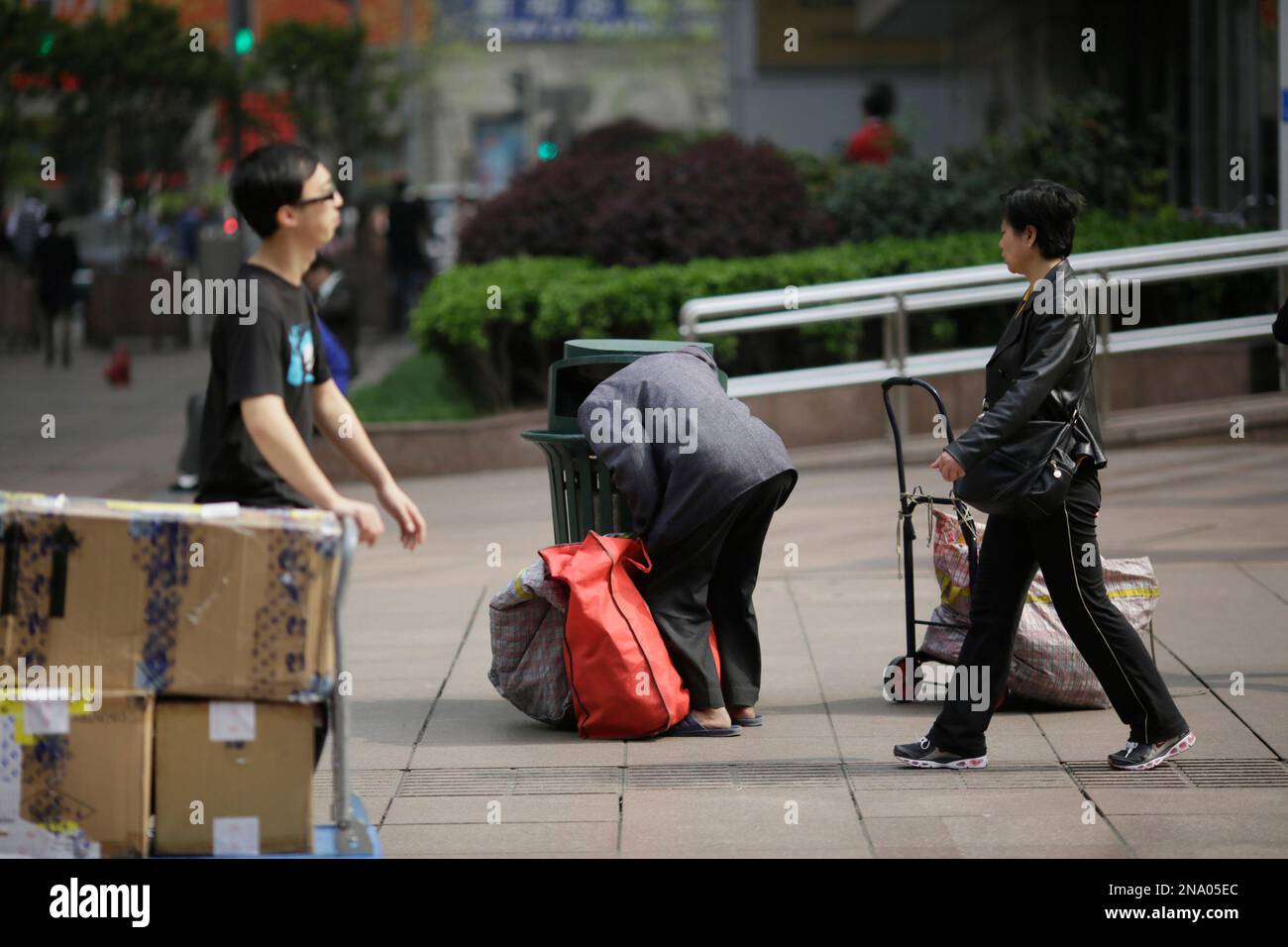 A garbage collector, center, looks for sellable materials from a public ...