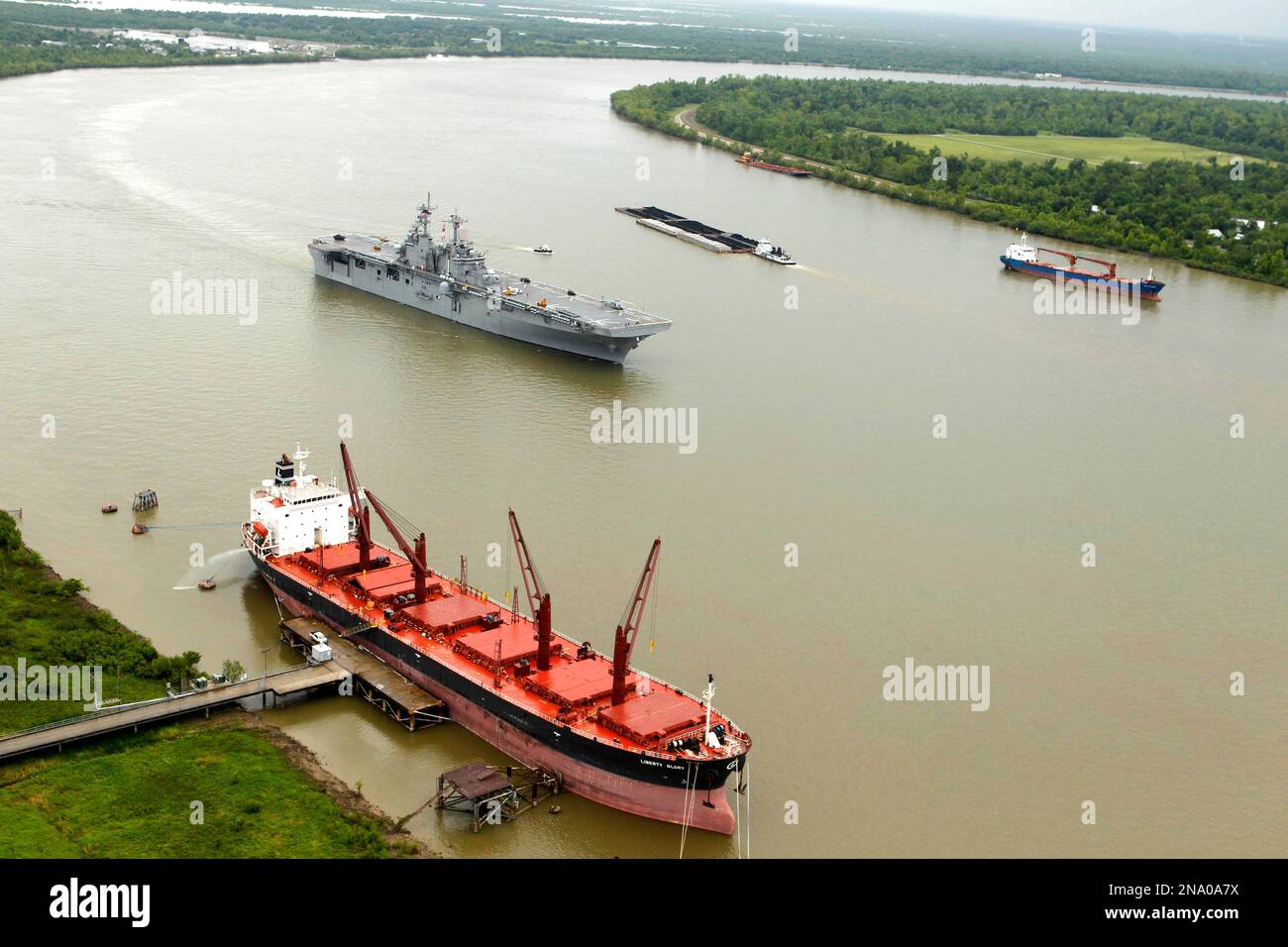 The USS Wasp, center,ships sails up the Mississippi River past tankers ...