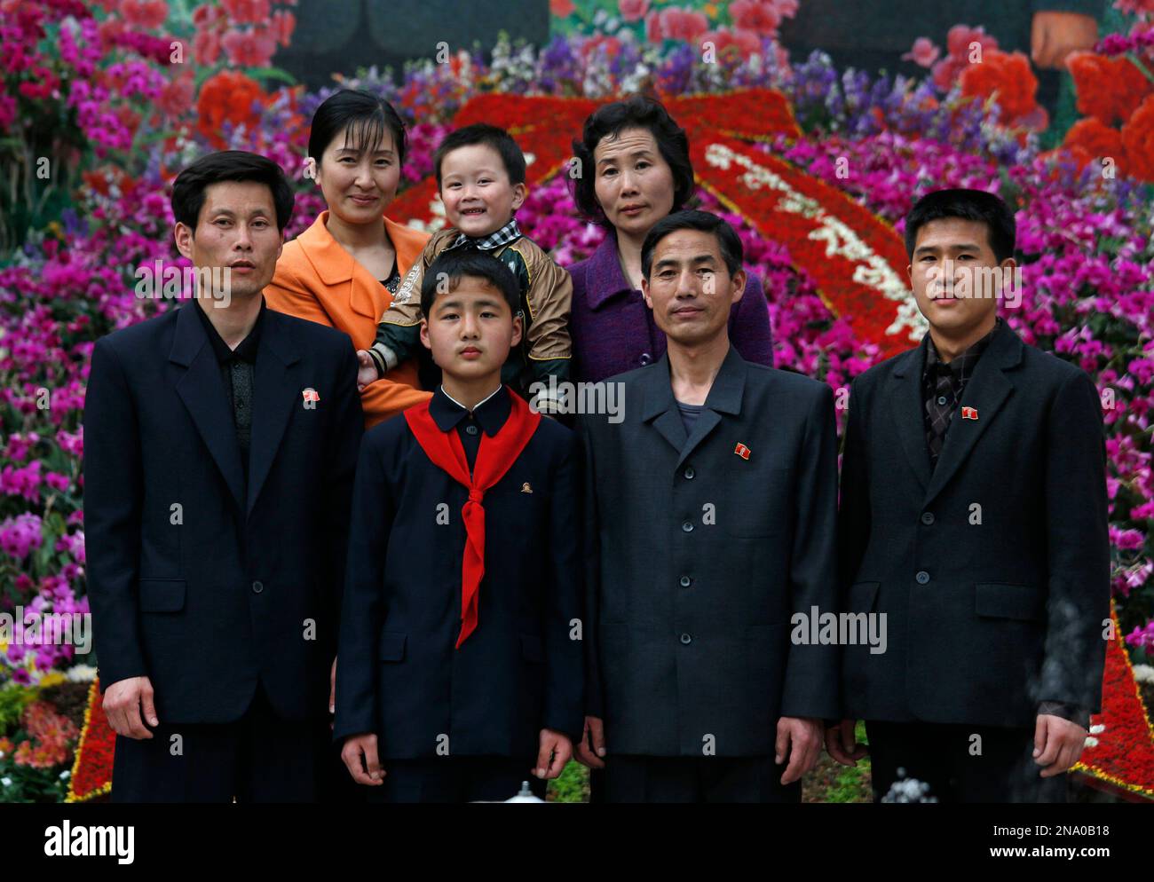 Family members pose for pictures in front of a display of "Kimilsungia ...