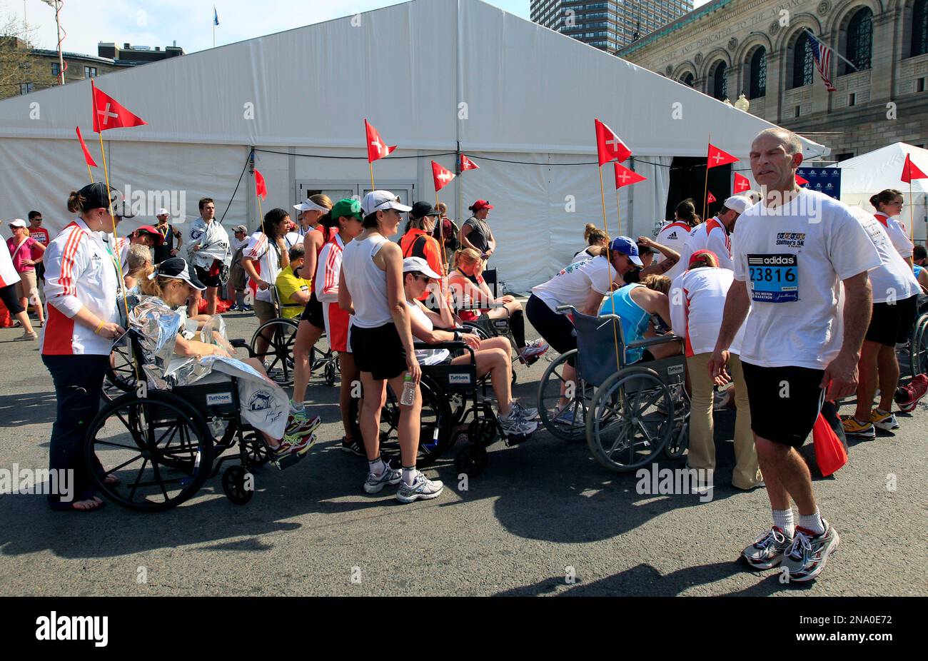 Runners wait in wheelchairs to get into the medical tent at the finish ...