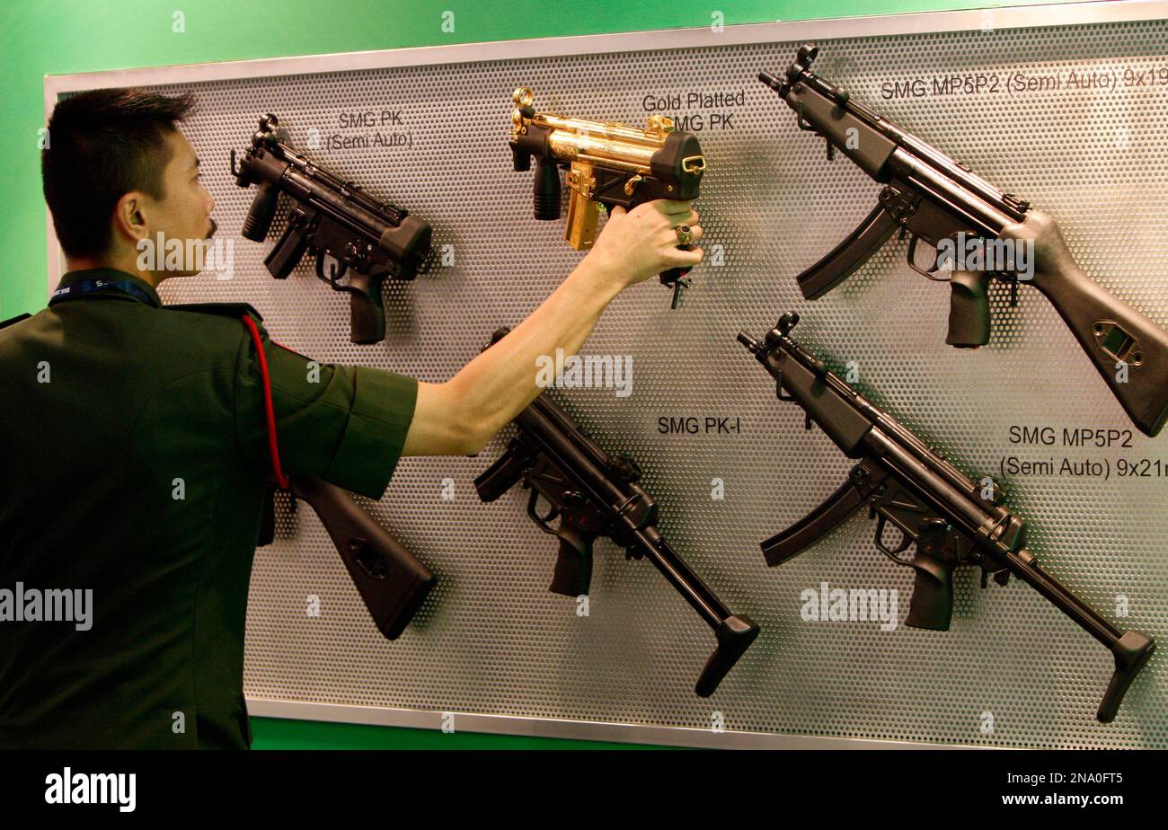 An army soldier tries out a gold plated sub-machine gun manufactured by ...