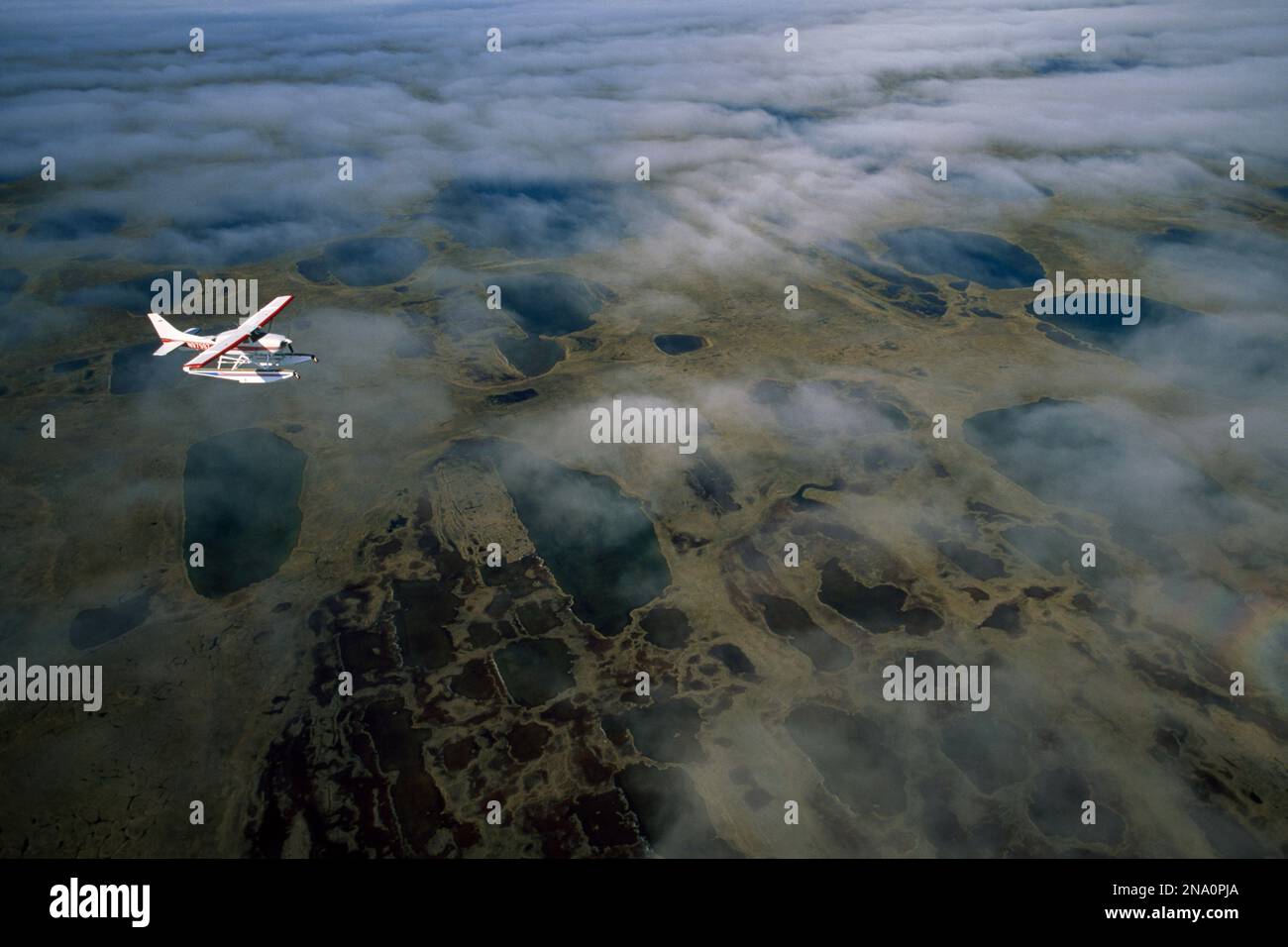 Seaplane over clouds and the tundra of Alaska's North Slope; North ...