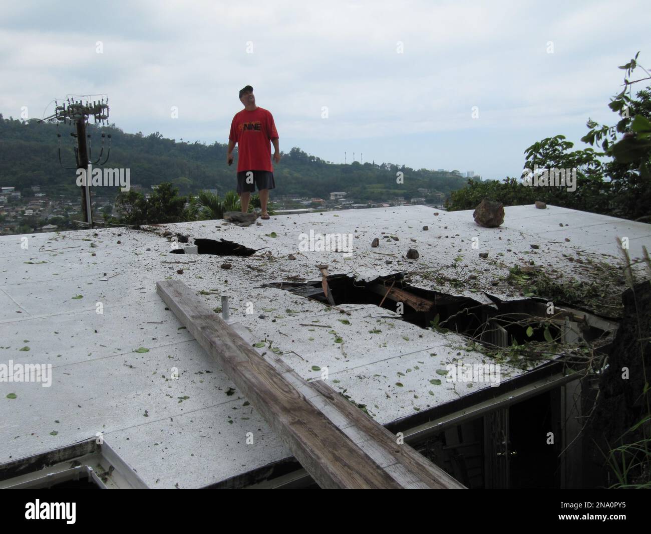 John "Keoni" Maemori's stands on the roof of his house while looking at ...
