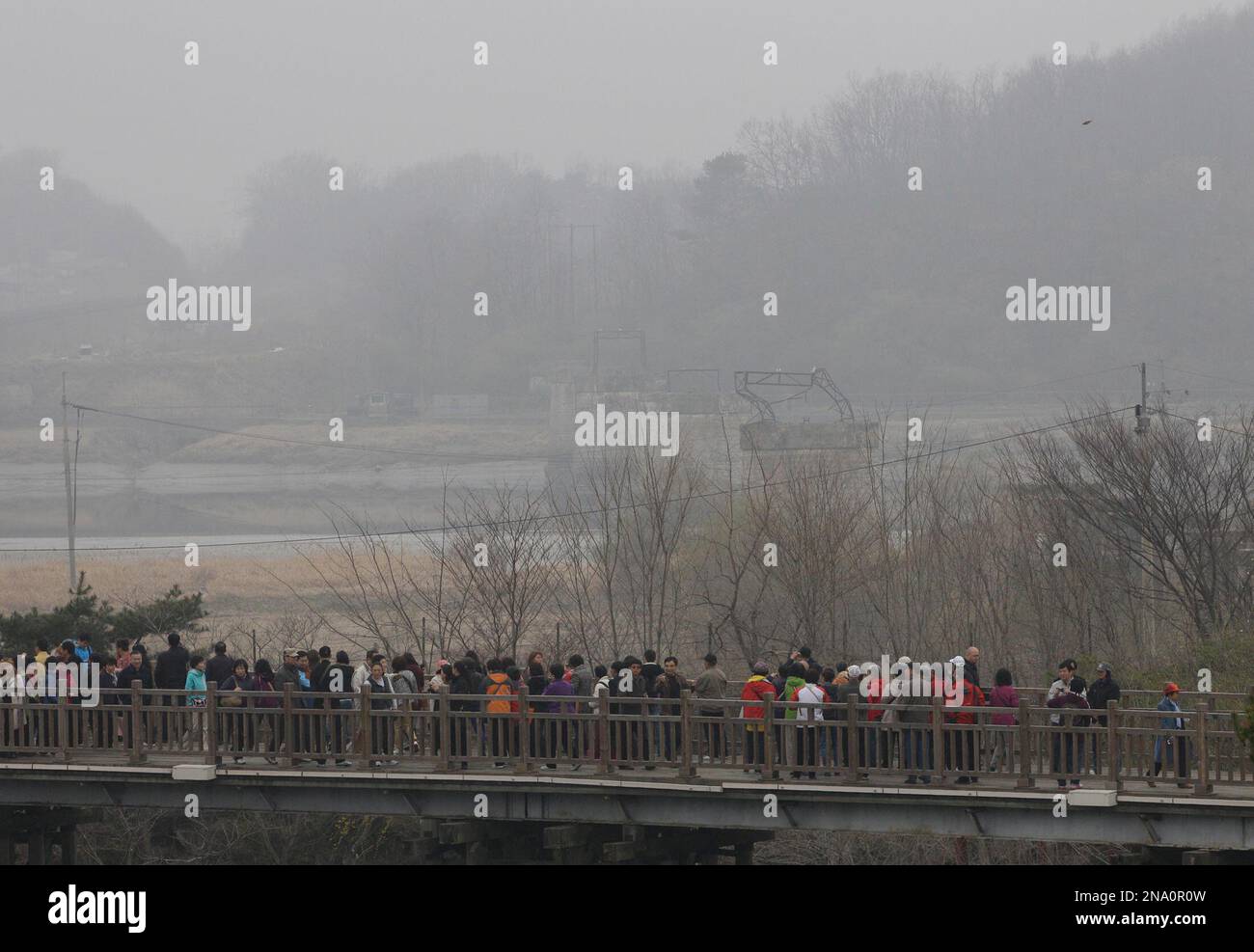 Tourists on a bridge look at the north side near the border village of ...