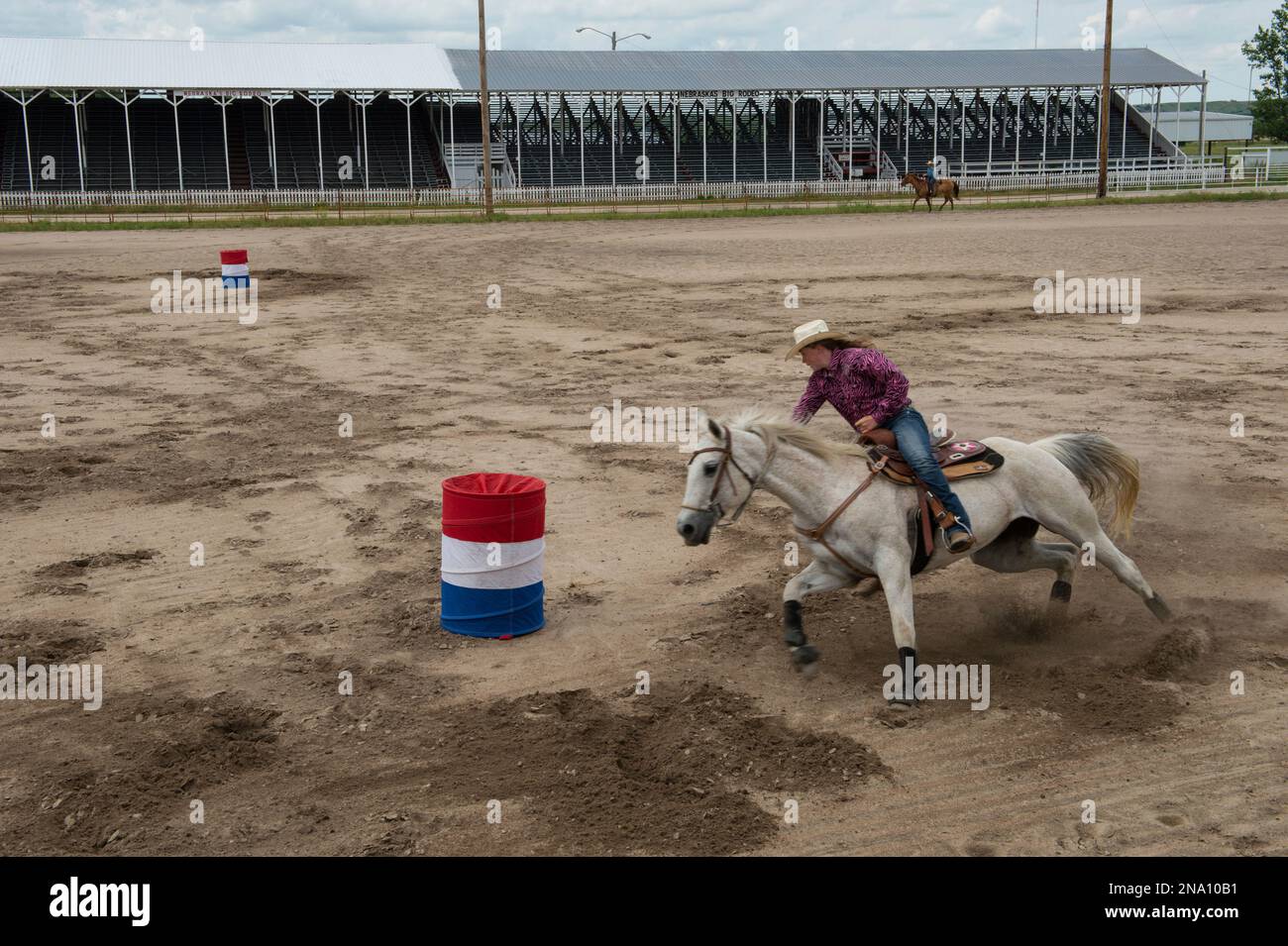 A teenage girl practices barrel racing with her horse; Burwell ...