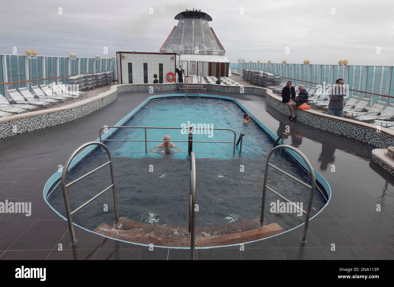 Passengers enjoy the swimming pool, on the deck aboard the MS Balmoral ...