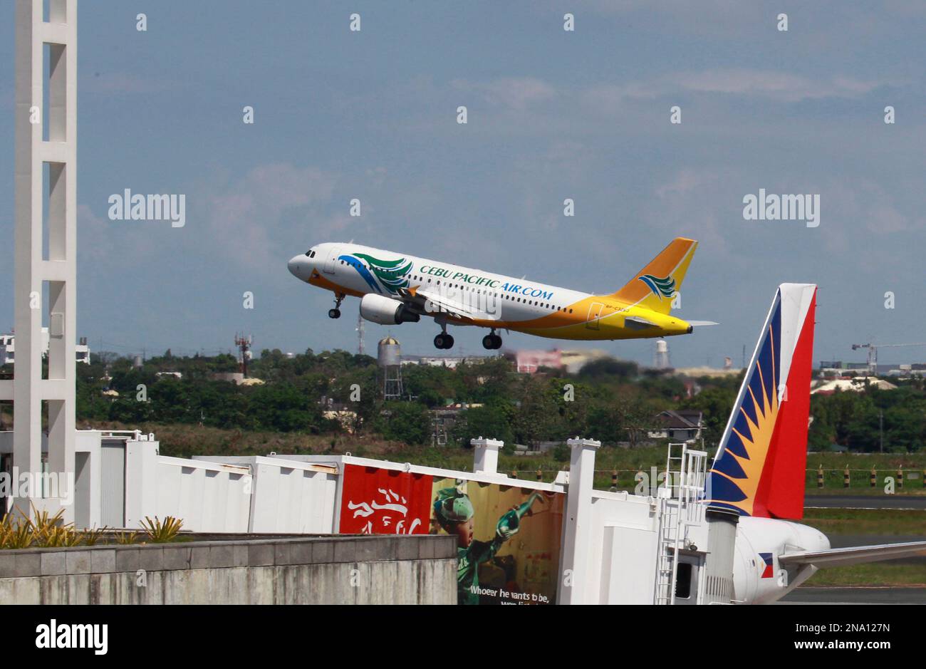 A Cebu Pacific passenger plane takes off with a Philippine Airlines ...
