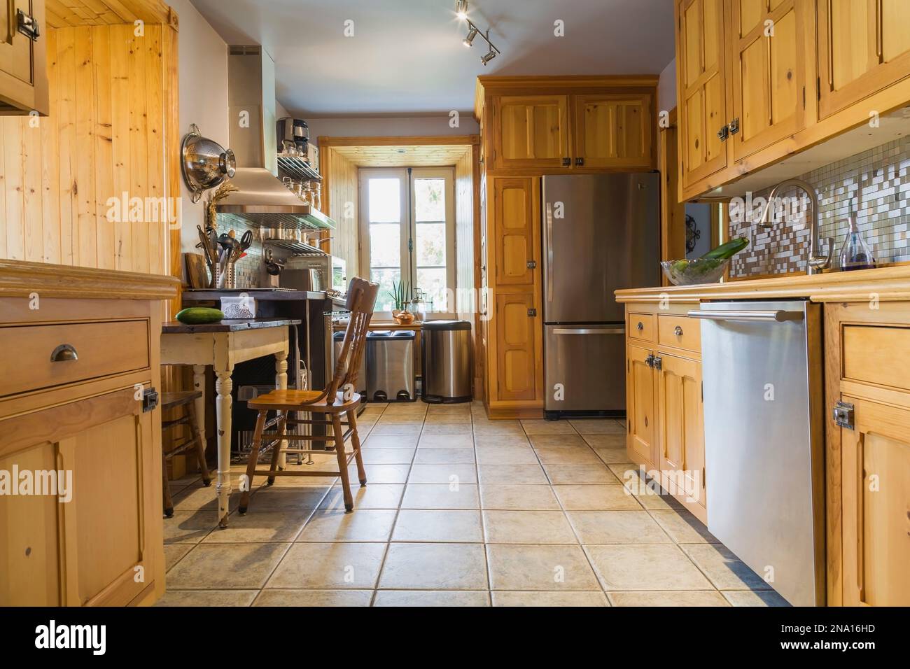 Pine wood cabinets and white antique breakfast table and chair plus stainless steel dishwater in ...