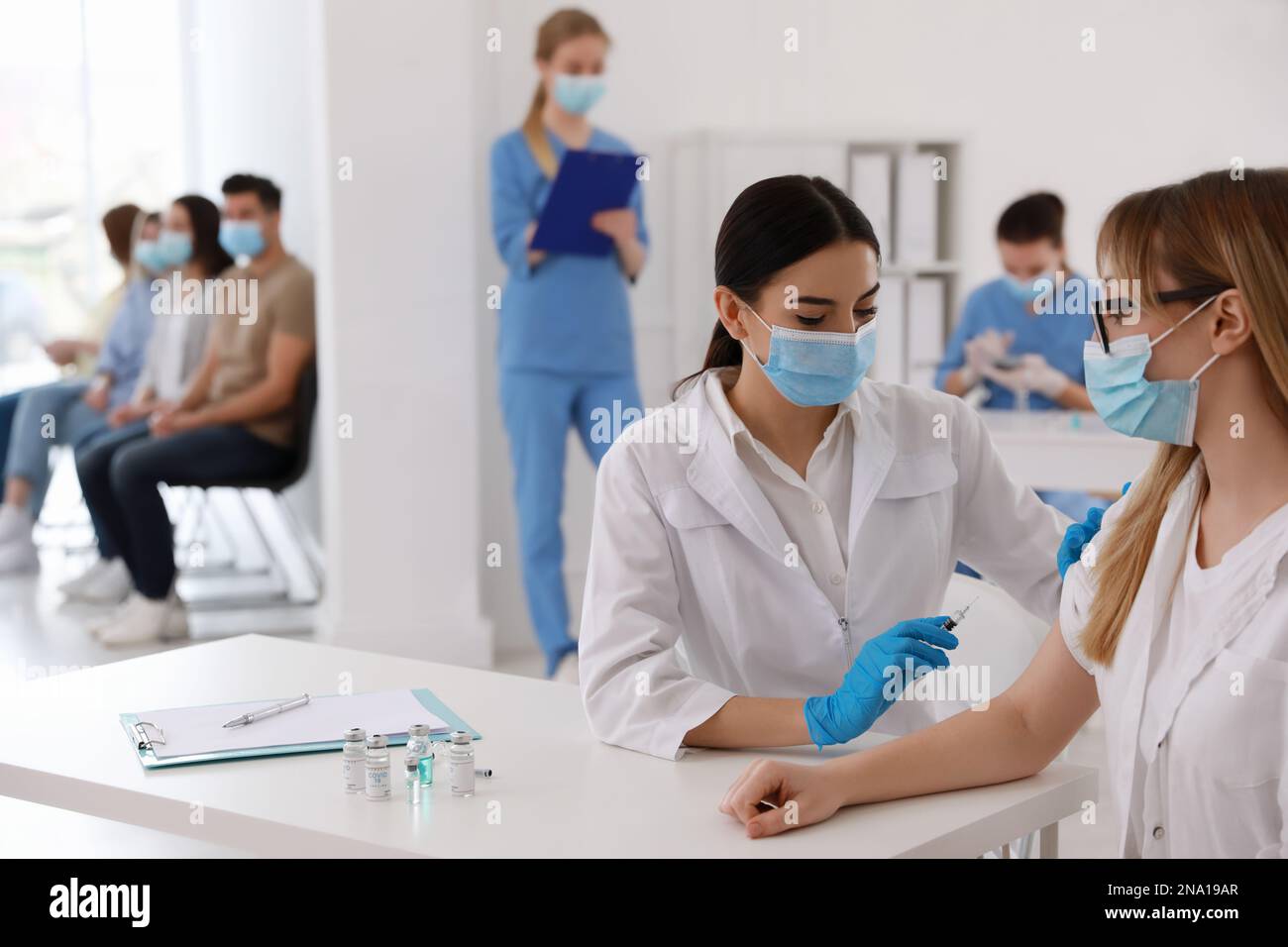 Doctor giving injection to patient while other waiting in line at ...