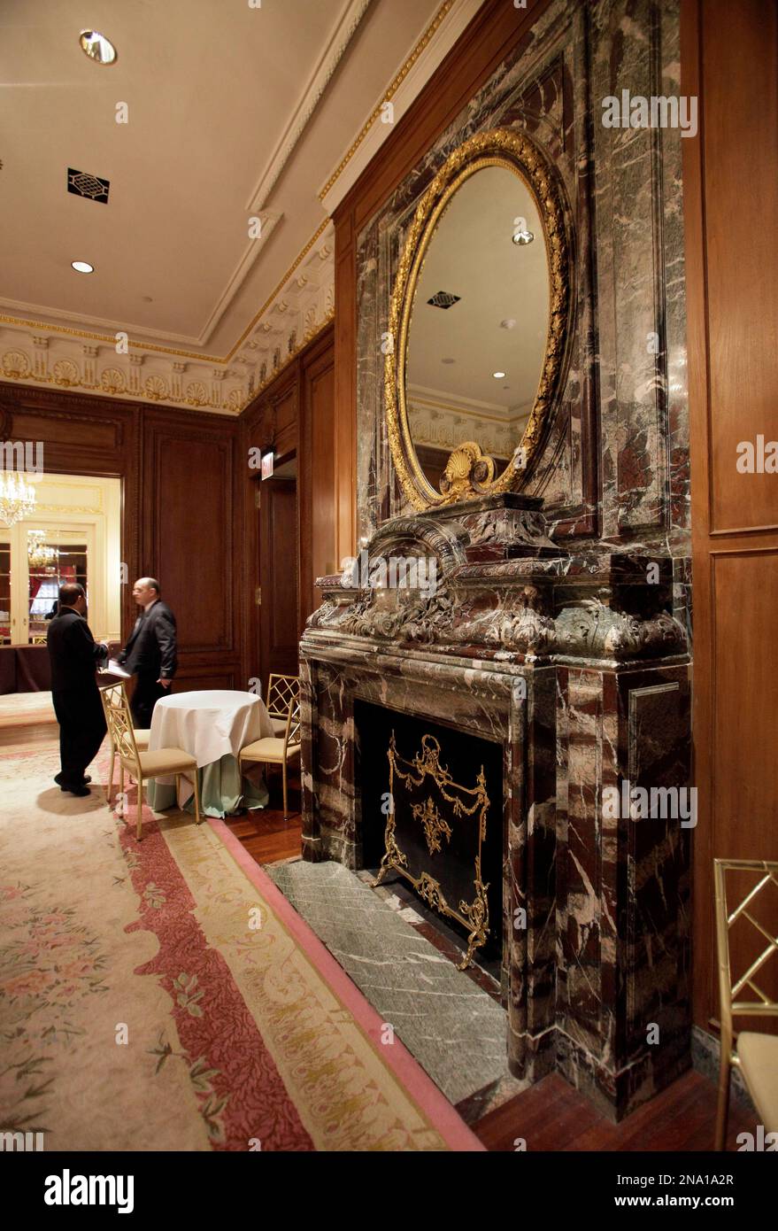 Two waiters confer near The Louis XVI fireplace of New York's St. Regis ...