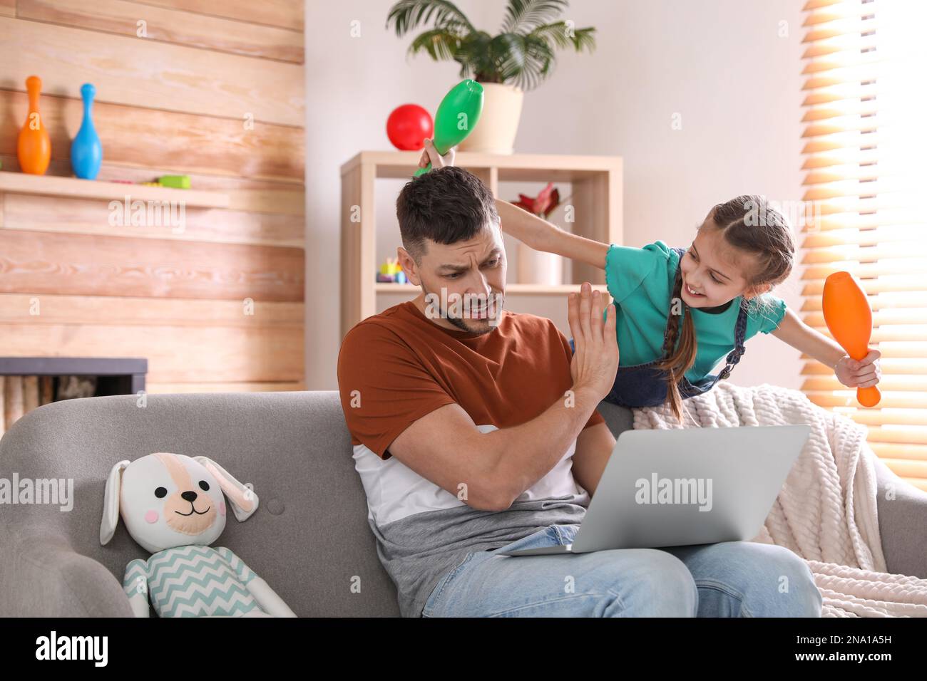 Cute child disturbing stressed man in living room. Working from home ...
