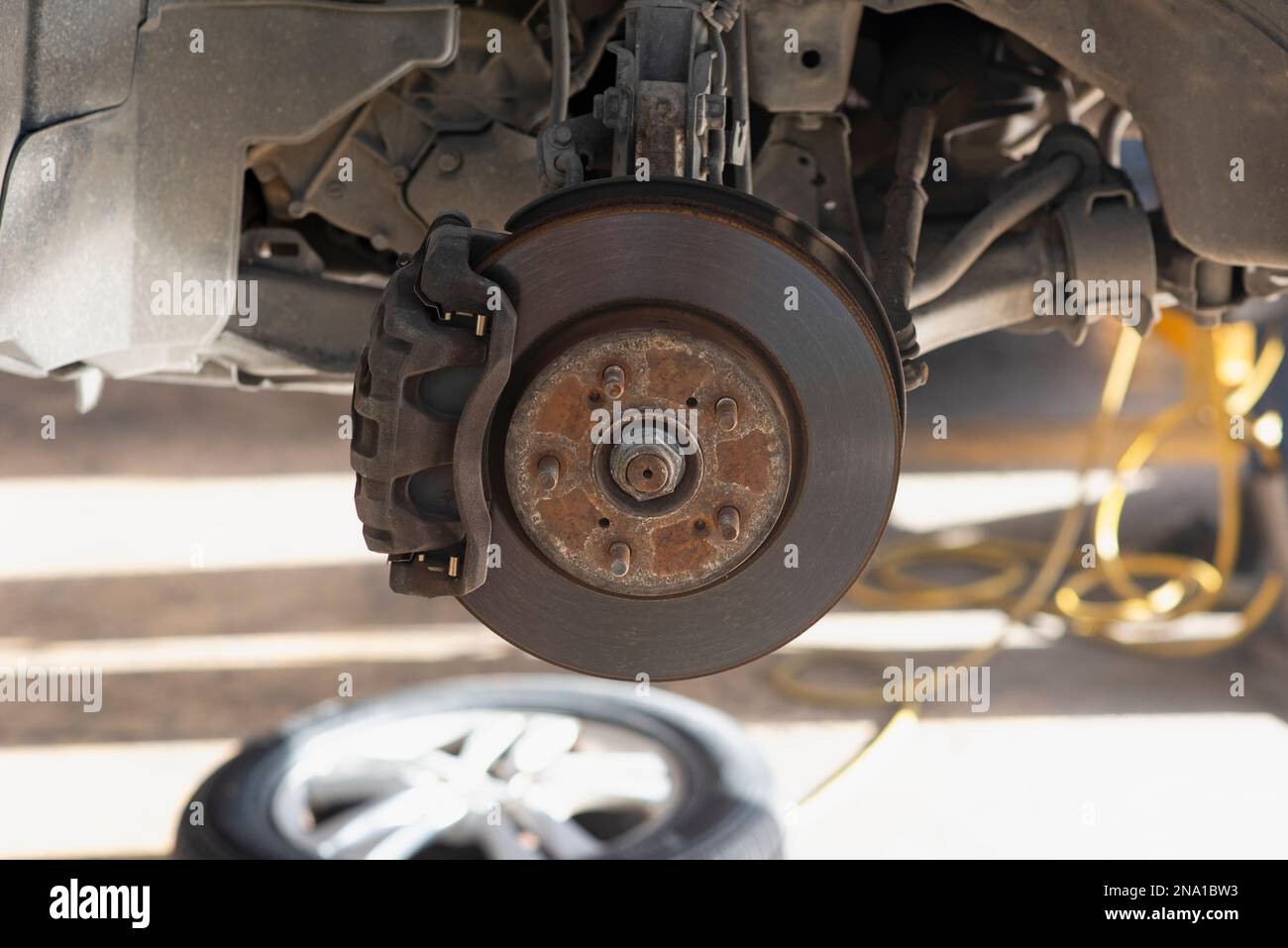 Car being serviced on lift deck, brake discs in foreground. Selective ...