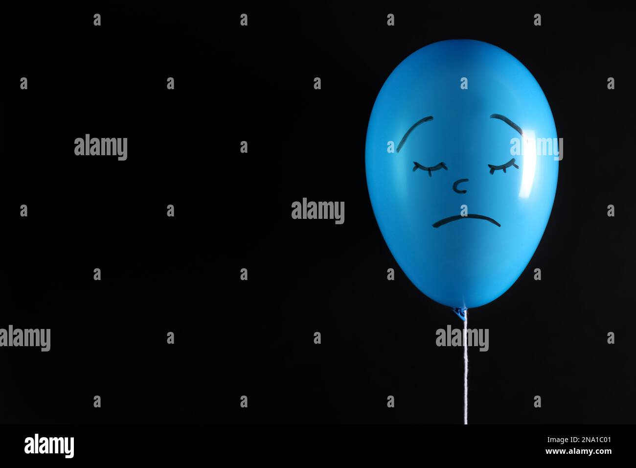 Air balloon with drawn sad face on black background. Space for text ...