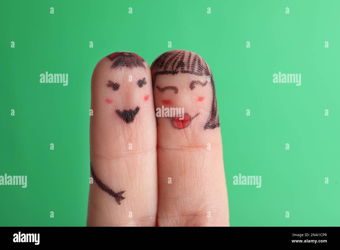 Two fingers with drawings of happy faces on green background. Spending ...