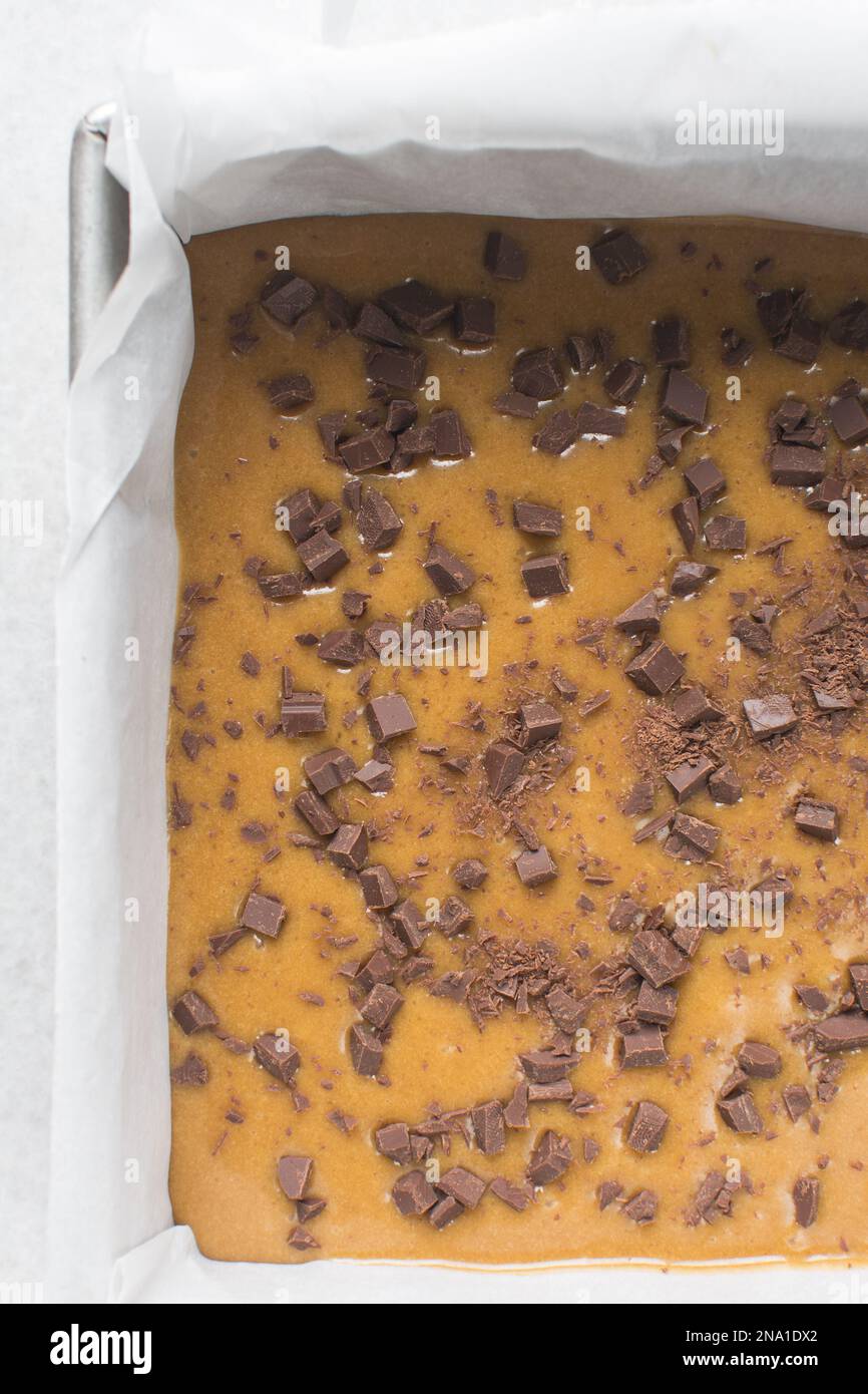 Blondie batter with chocolate chips in a parchment lined square baking ...