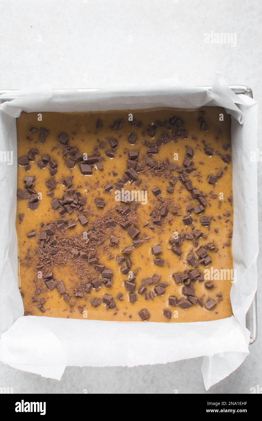 Blondie batter with chocolate chips in a parchment lined square baking ...